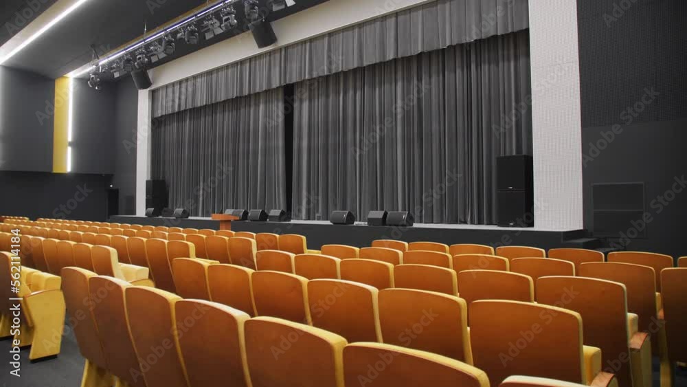 Chair rows and stage with black curtain in empty hall of theatre ...