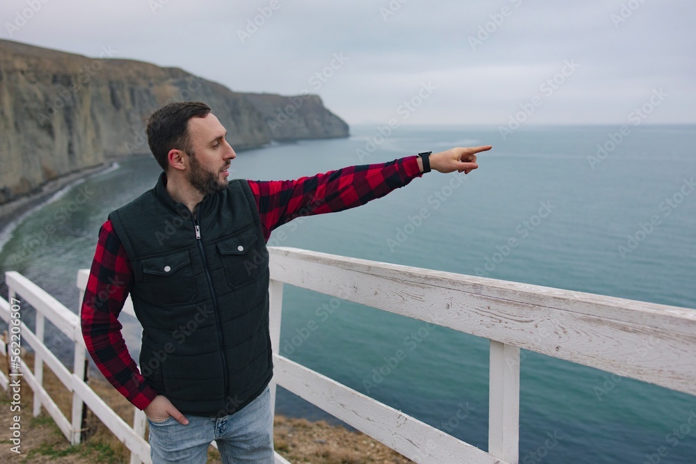 Side view of a tourist pointing with his hand in the right direction ...