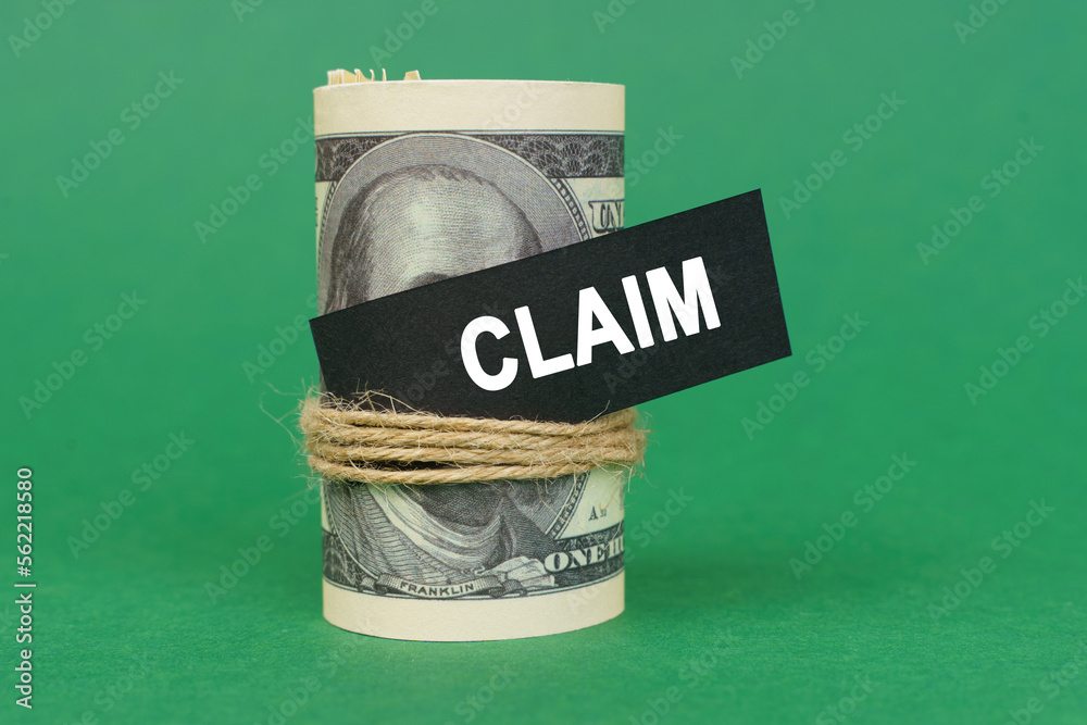 On a green surface, rolled dollars with a black sign that says - CLAIM ...
