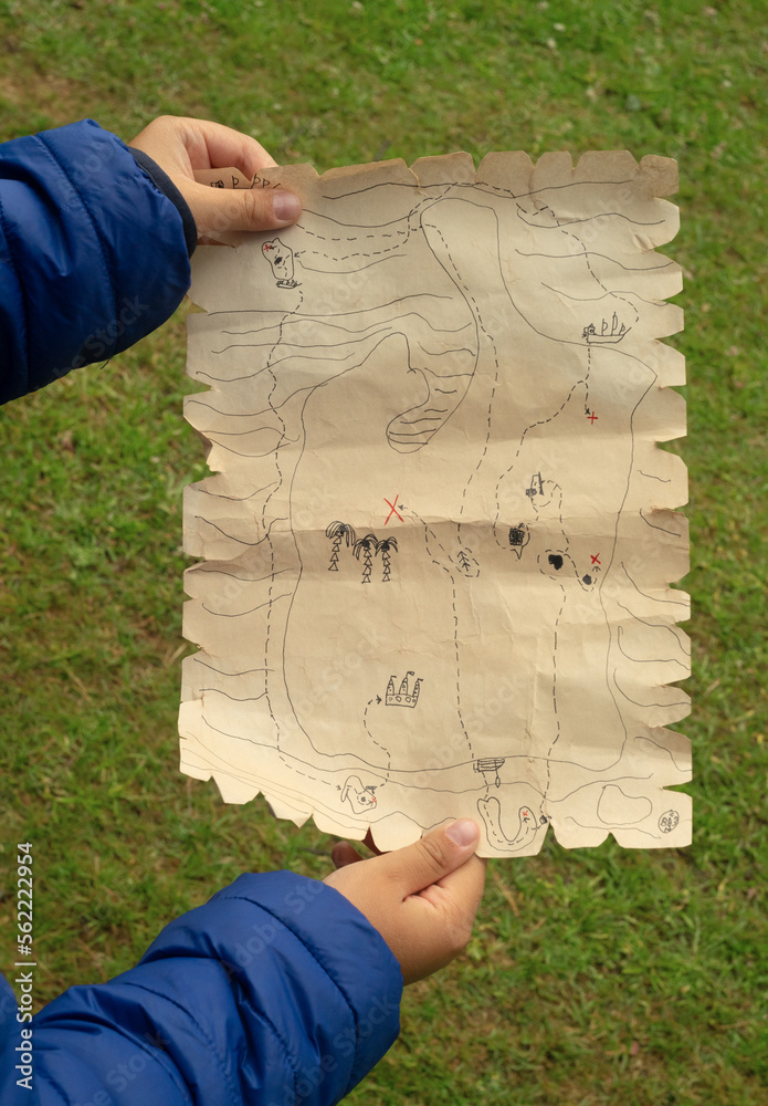 The child's hands hold a treasure map. A game of pirates in the fresh ...