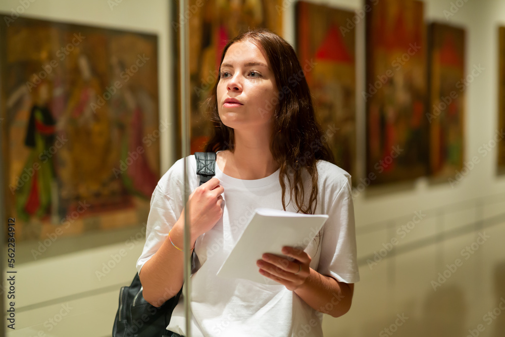 Foto de Focused girl visiting an exhibition in a museum looks with ...