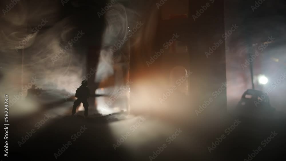 Army sniper with large caliber rifle standing in the fire and smoke ...