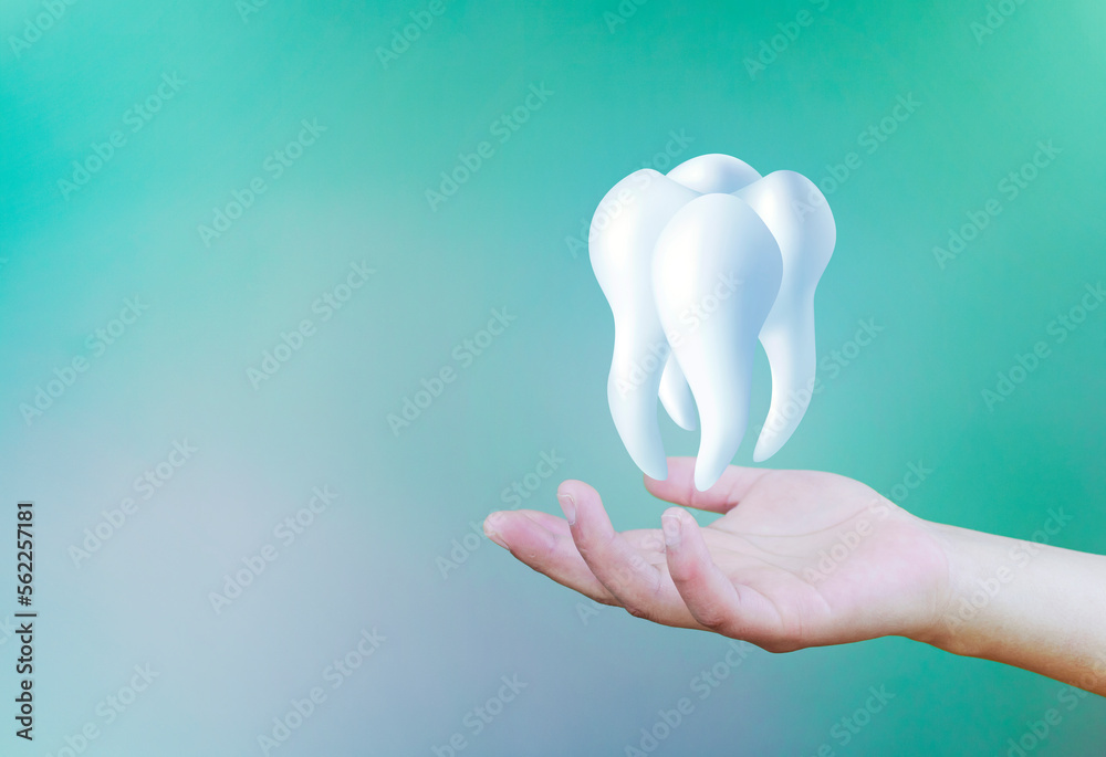 The hand holds a molar tooth on an emerald green background, dental ...