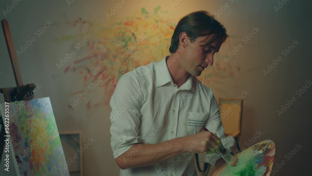 In front of the camera in art studio the artist guy very handsome ...