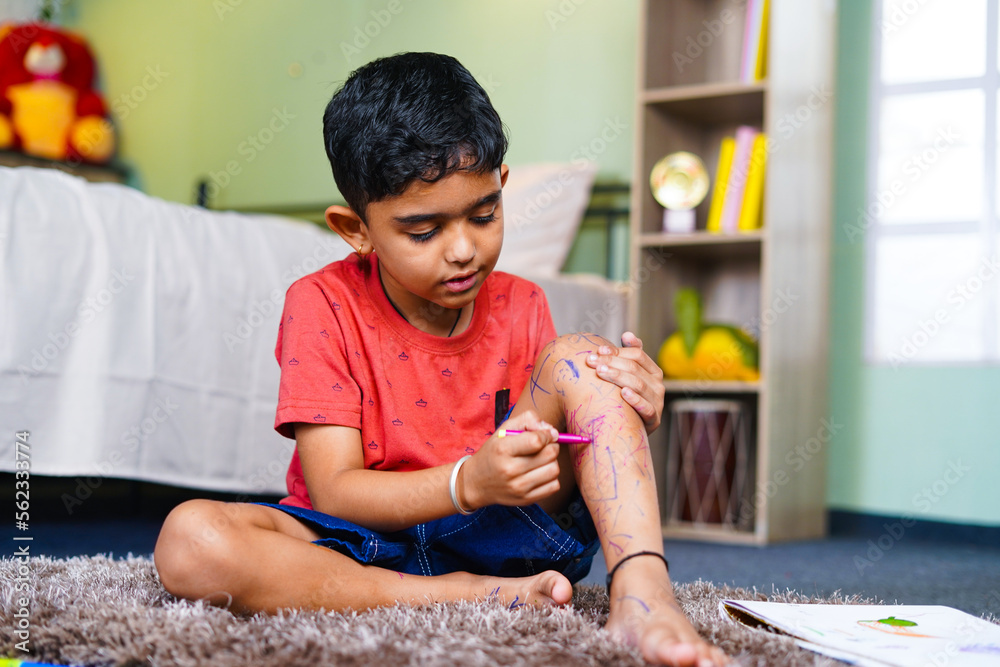 Preteen playful kid making drawings on leg using sketch pens at home ...