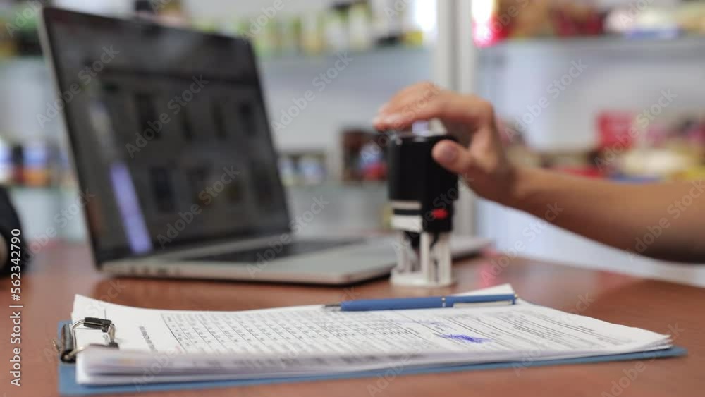 Close up of secretary, businesswoman putting stamp, seal on document ...