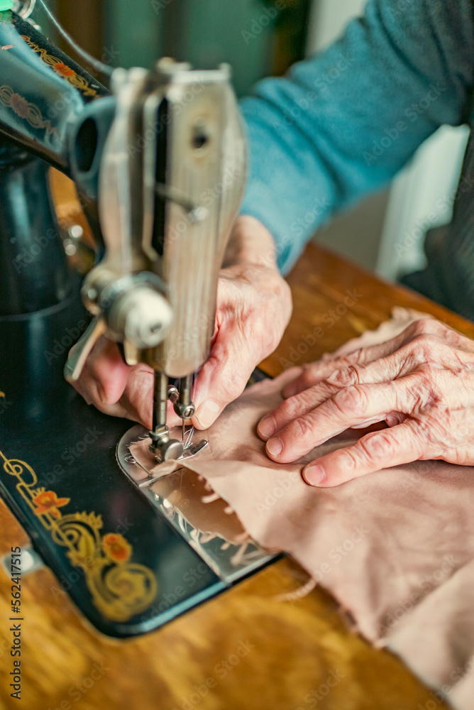 Senior woman in spectacles use sewing machine. wrinkled hands of the ...