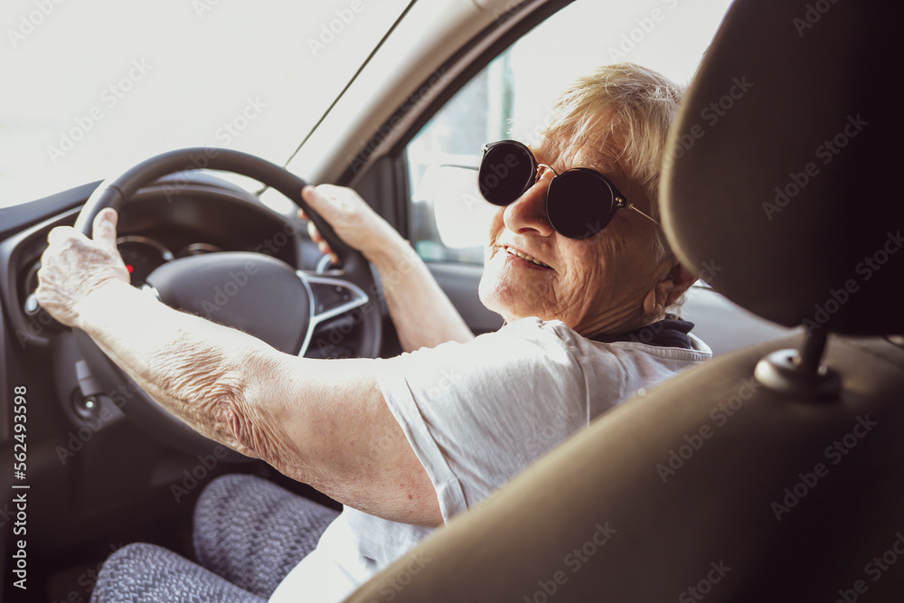 A happy elderly woman is driving a car. Grandma got her driver's ...