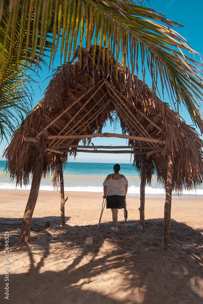 Foto de beautiful young amputee woman with crutches standing on a beach ...