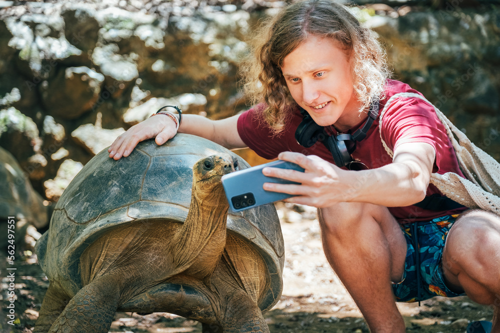 Smiling tourist boy making a selfie using cell phone with Aldabra giant ...