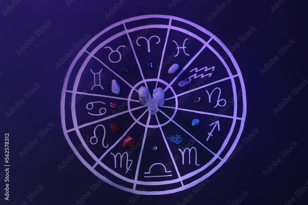 Natural stones for zodiac signs and drawn astrology chart on dark blue ...