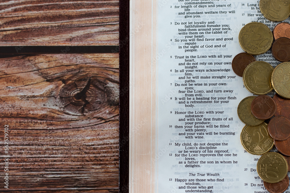 Coin money on top of open Holy Bible. Copy space, top view. Concept of ...