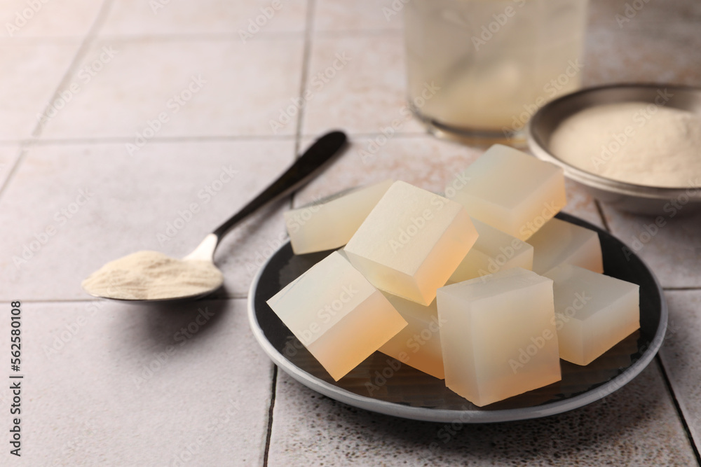 Agar-agar jelly cubes and powder on tiled surface, closeup Stock Photo ...