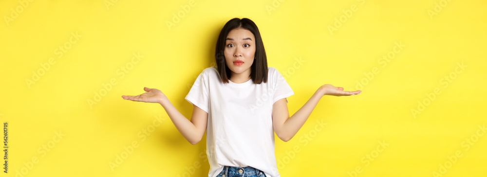 Clueless asian girl shrugging shoulders, spread out hands and looking ...