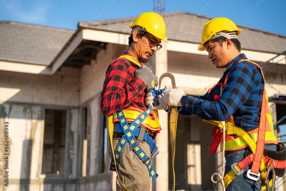Asian two workers helping each other wearing fall protection suits with ...