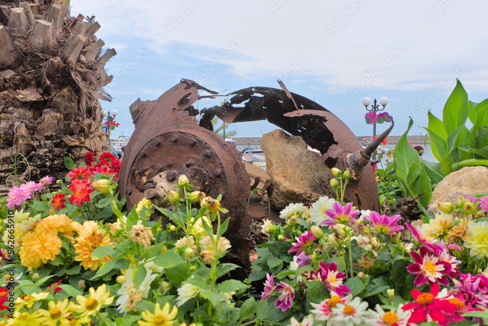 Antique rusty naval mine with holes in the front garden of bright multi ...