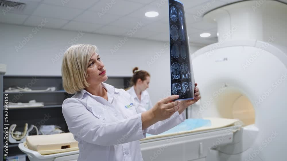Medic in white robe holds MRI scan ob brain. Nurse lays the sheet on ...