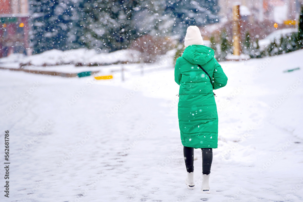 Woman walking alone on snowy city street during blizzard. Woman in ...