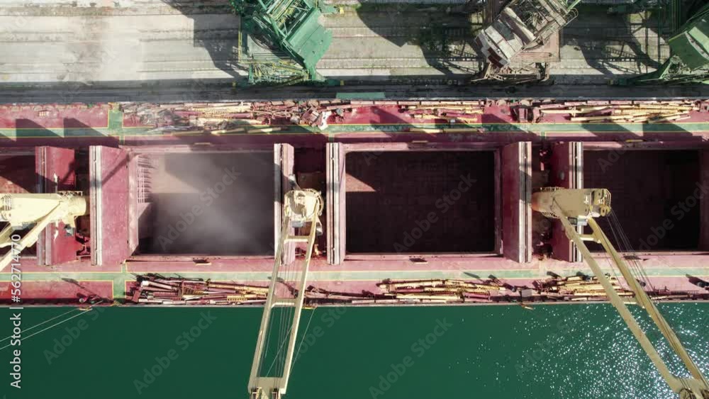 Vidéo Stock Loading dry cargo ship of wheat by cranes in port. Aerial view loading into holds of ...