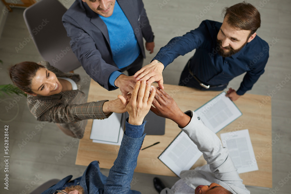 Happy business team joining hands after successful work meeting ...