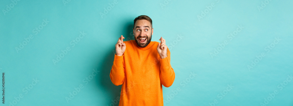 Excited man expecting something with anticipation, hold fingers crossed ...