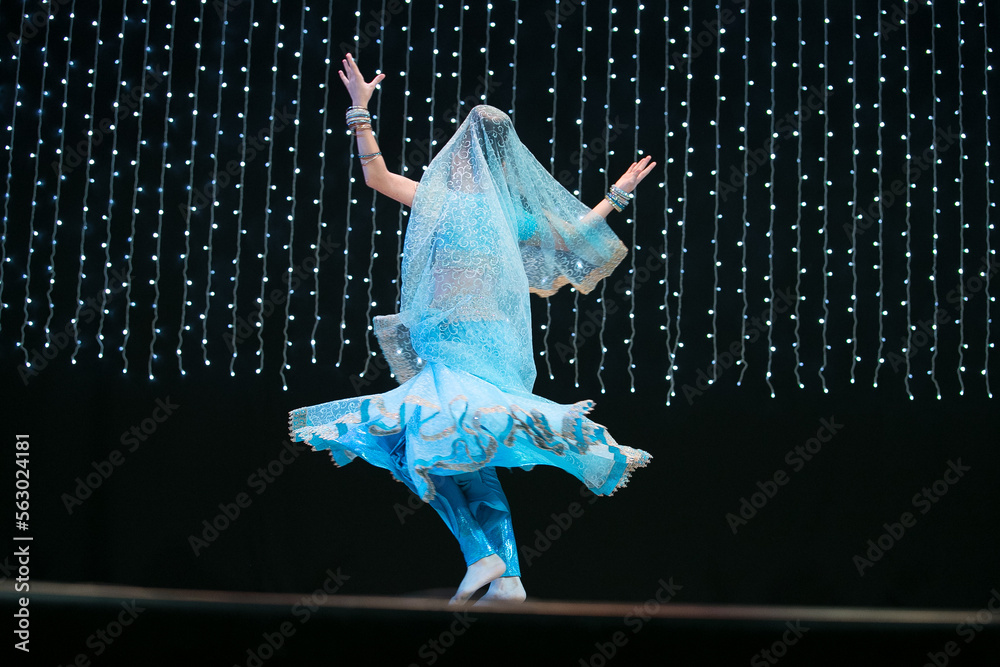 A young dancer with long hair in an oriental costume with a multi ...