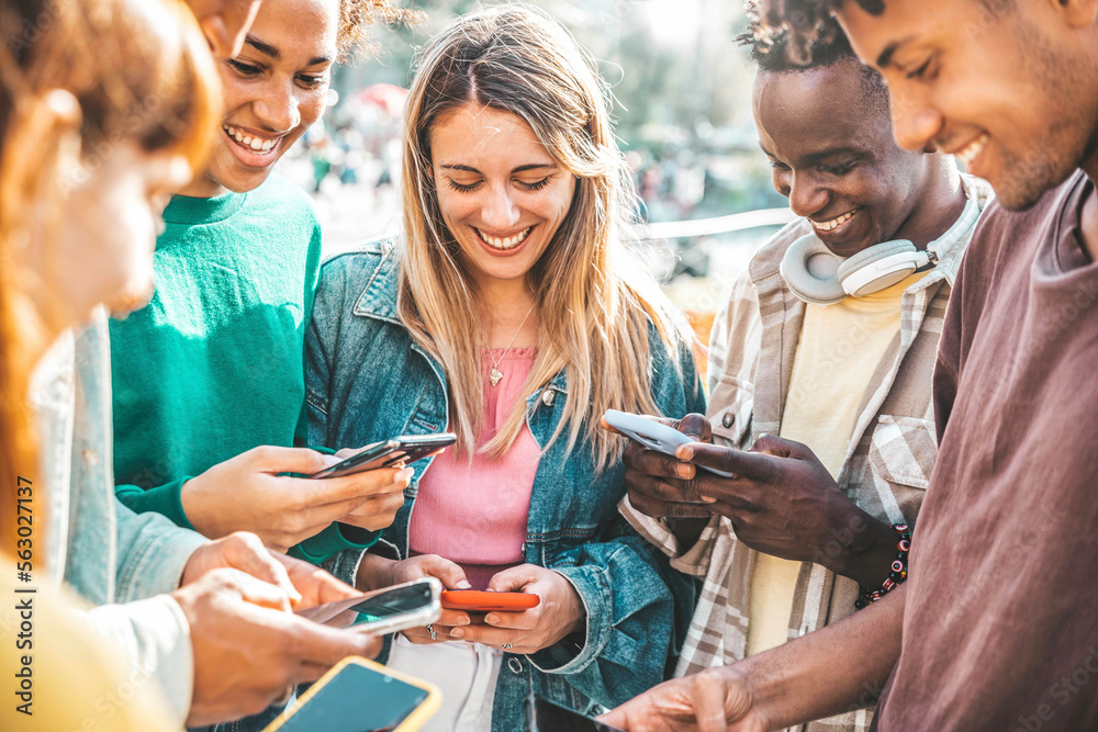 Happy group of multiracial teens using smart mobile phone outdoors - Diverse university students ...