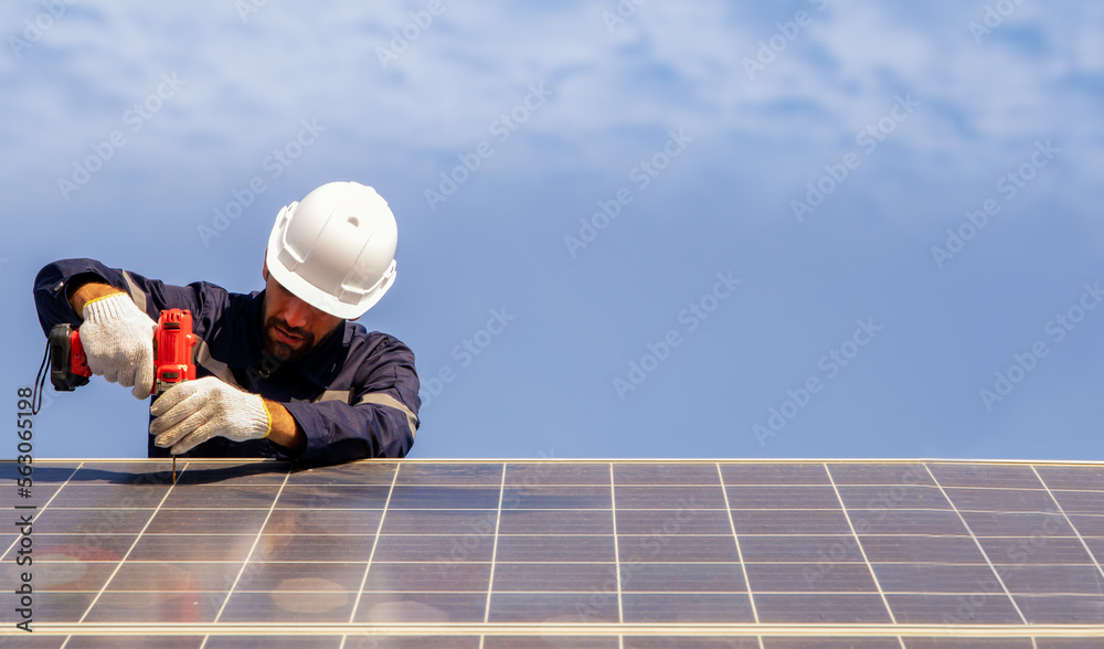 Male technician installing solar panel using electric drill securing ...