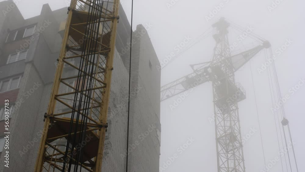 A construction crane is working on a foggy day. Reconstruction or ...