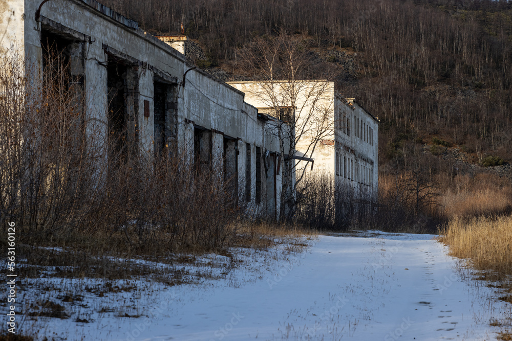 Snow-covered street of an abandoned town. View of old empty buildings ...