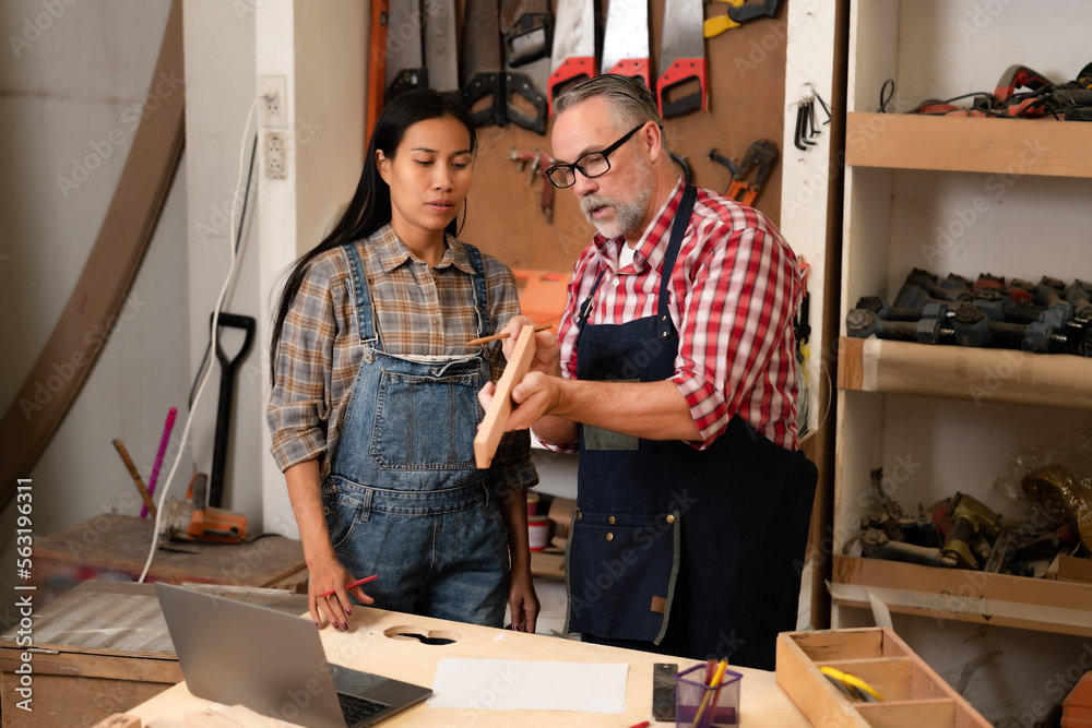 Professional elderly carpenter talking with assistant about wood plank ...