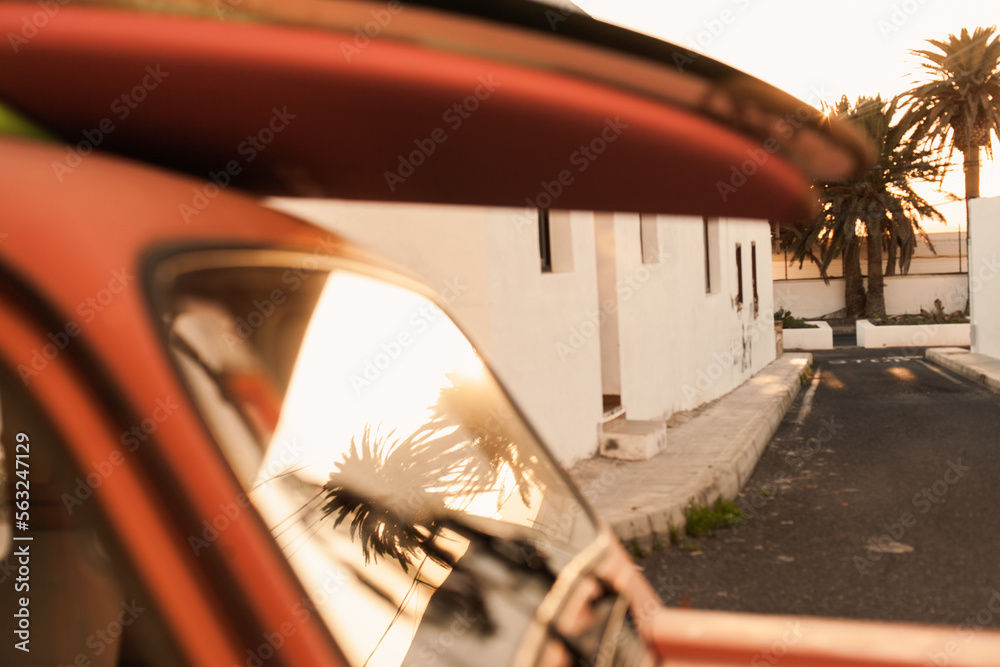 A stack of surfboards on a retro car roof with sun shining. Summer and ...
