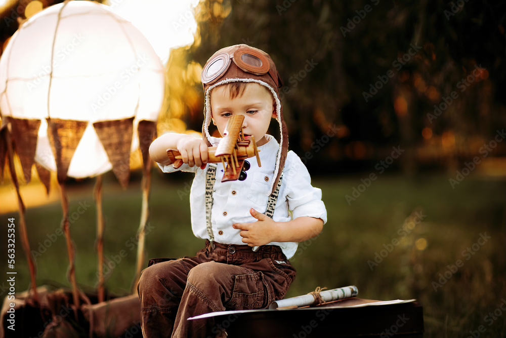 Little pilot boy in vintage aviator hat sitting and playing with small ...