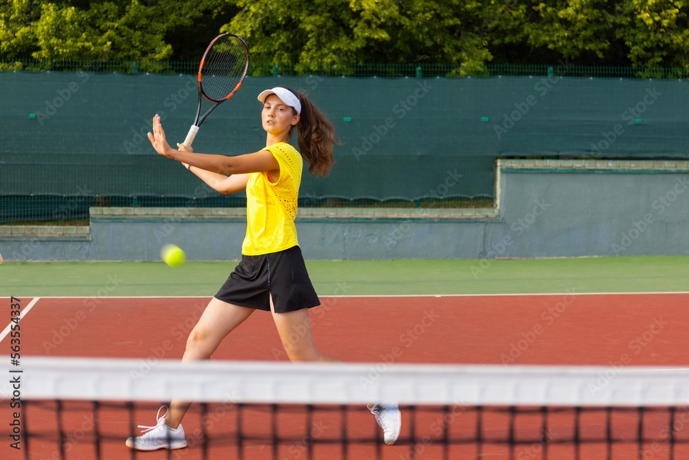 Professional equipped female tennis player beating hard the tennis ball ...