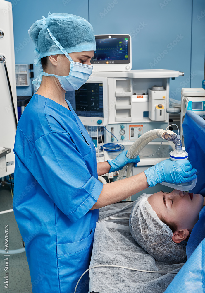 Foto de Surgical nurse in sterile gloves placing anesthesia mask on ...