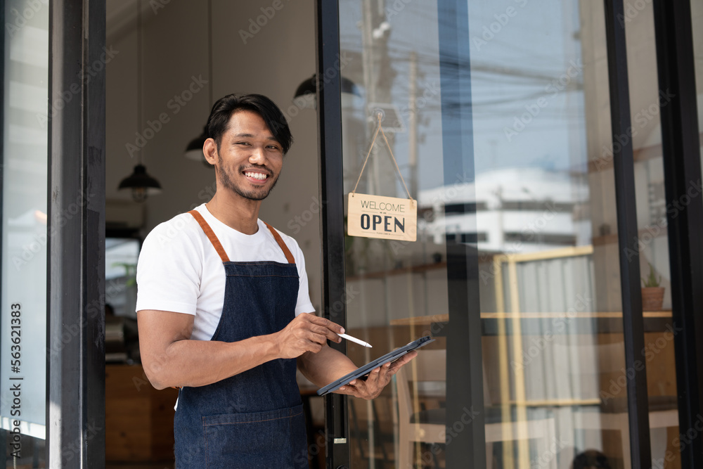 Portrait of smiling owner standing at his restaurant gate with open ...