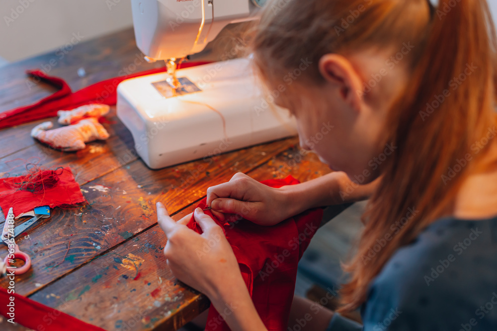 Handsome cute teenager sews at home on a sewing machine. Serious woman ...