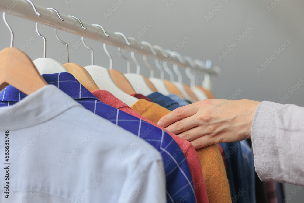 women's hands sort through clothes in wardrobe on hangers, shopping and ...