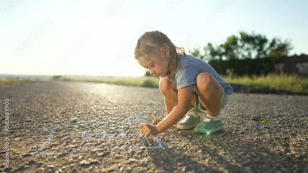 Girl on the playground. Child draws on the pavement with chalk ...