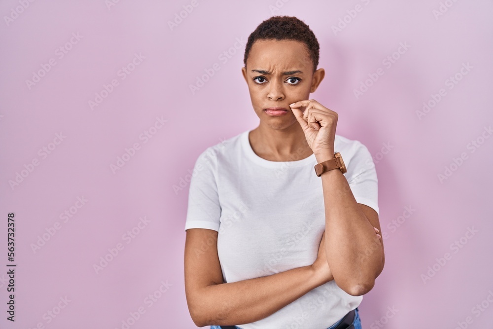 Beautiful african american woman standing over pink background mouth ...