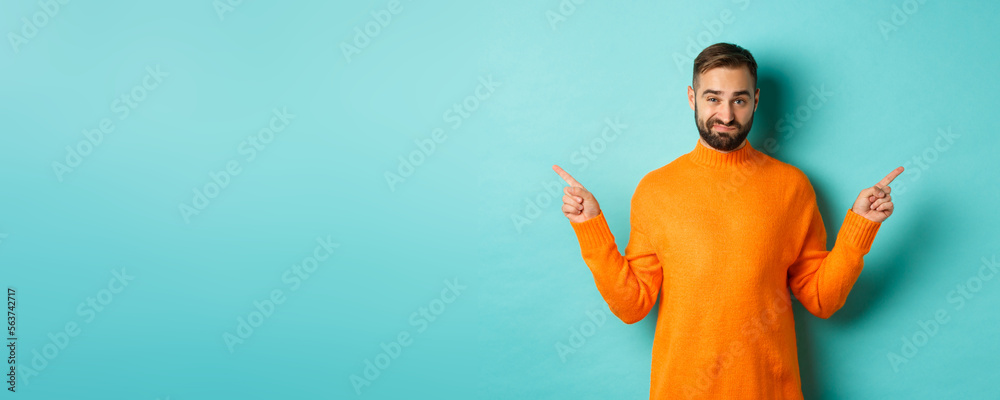Doubtful and indecisive man pointing fingers sideways, showing ...