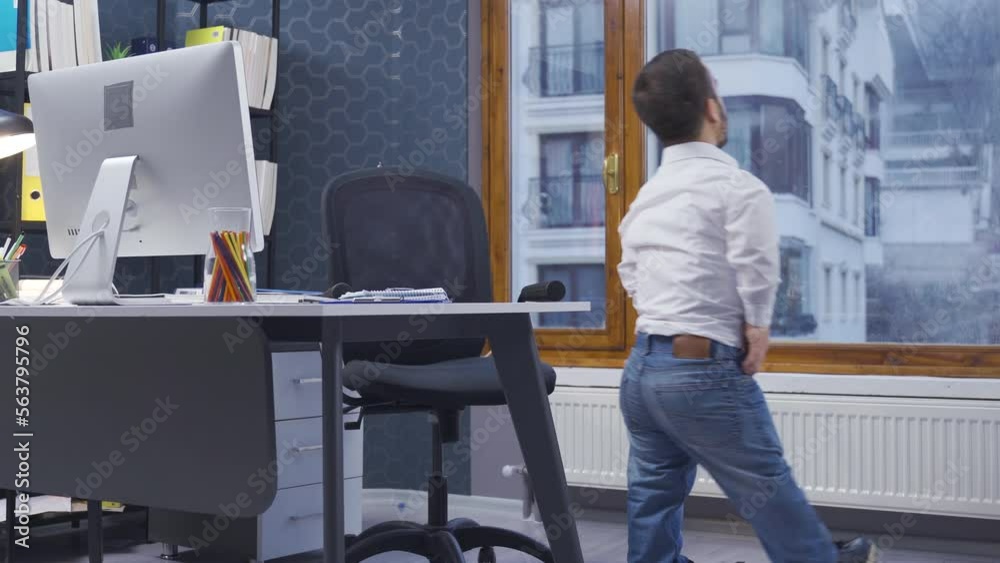 Happy midget man working in his office. He gets up and looks outside ...