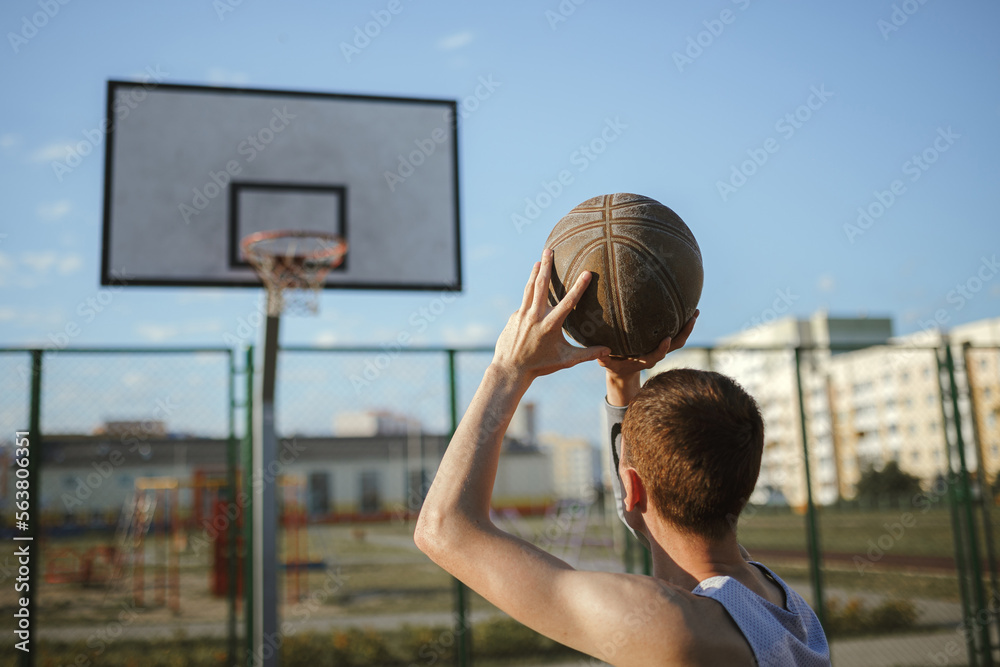 Back view of male basketball player playing streetball and aiming in ...