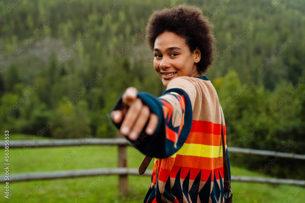 Young woman reaching her arm forward while walking in green forest ...