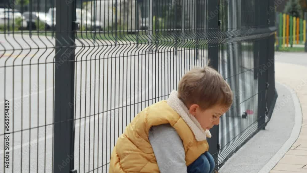 Little upset boy being victim of school bullying crying next to metal ...