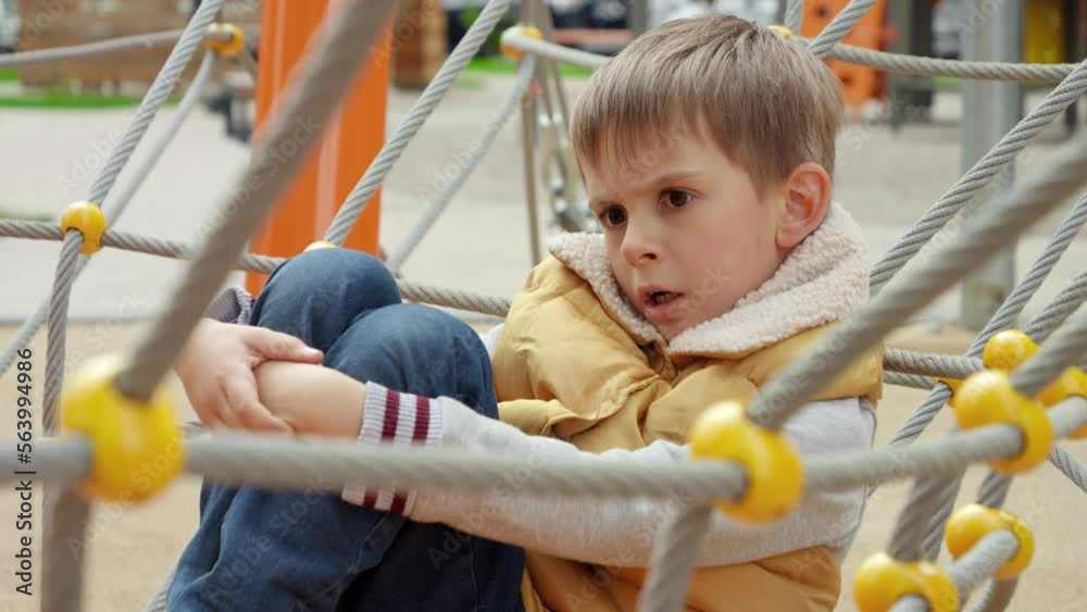 Sad lonely boy having no friends sitting on playground alone. Child depression, problems with ...