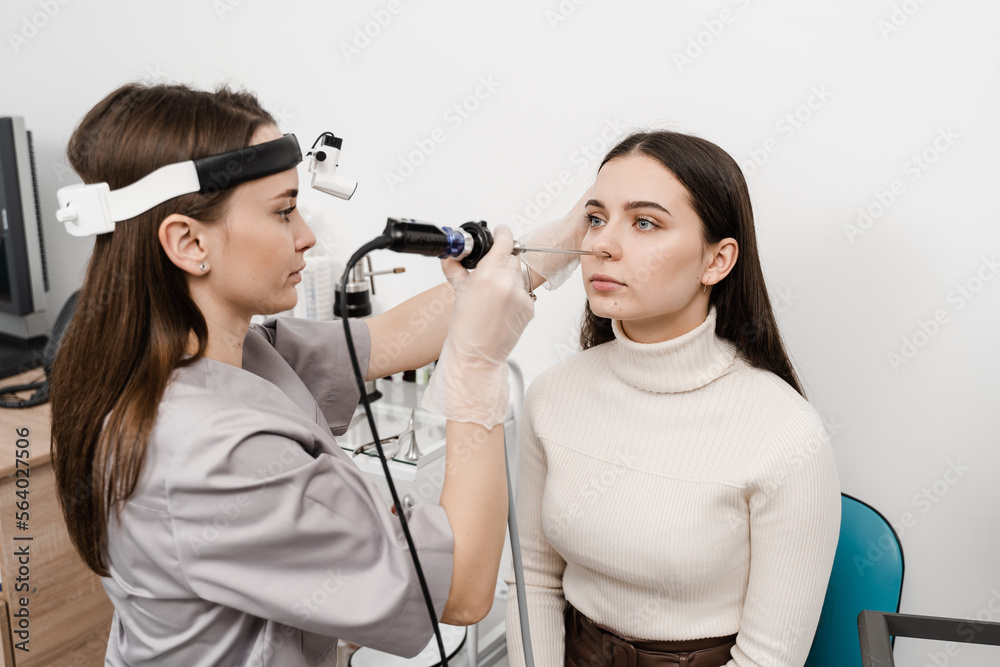 ENT doctor otolaryngologist with headlight treat nose woman patient ...