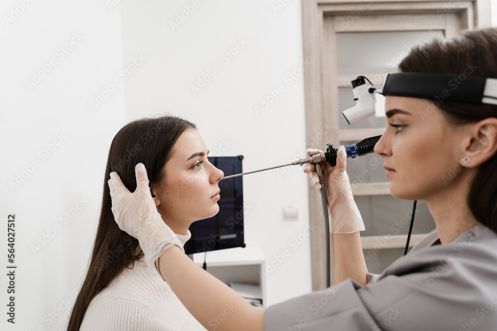 ENT doctor otolaryngologist with headlight treat nose woman patient ...