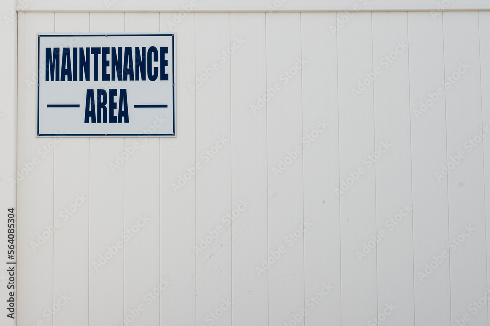 A white wooden fence with a small sign in the left corner. The sign is ...