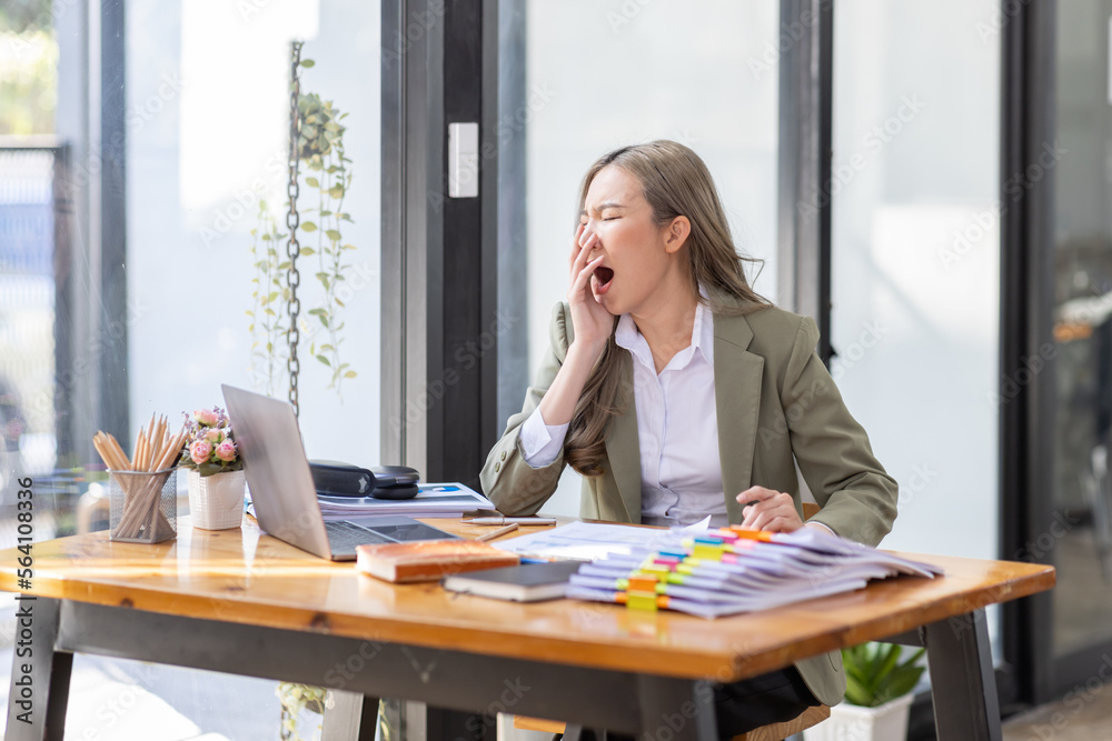 Foto de Bored Young business Asian woman sitting at her workplace at ...